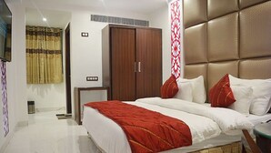 Quarto de hotel com cama, guarda-roupa, uma mesinha e espelho.