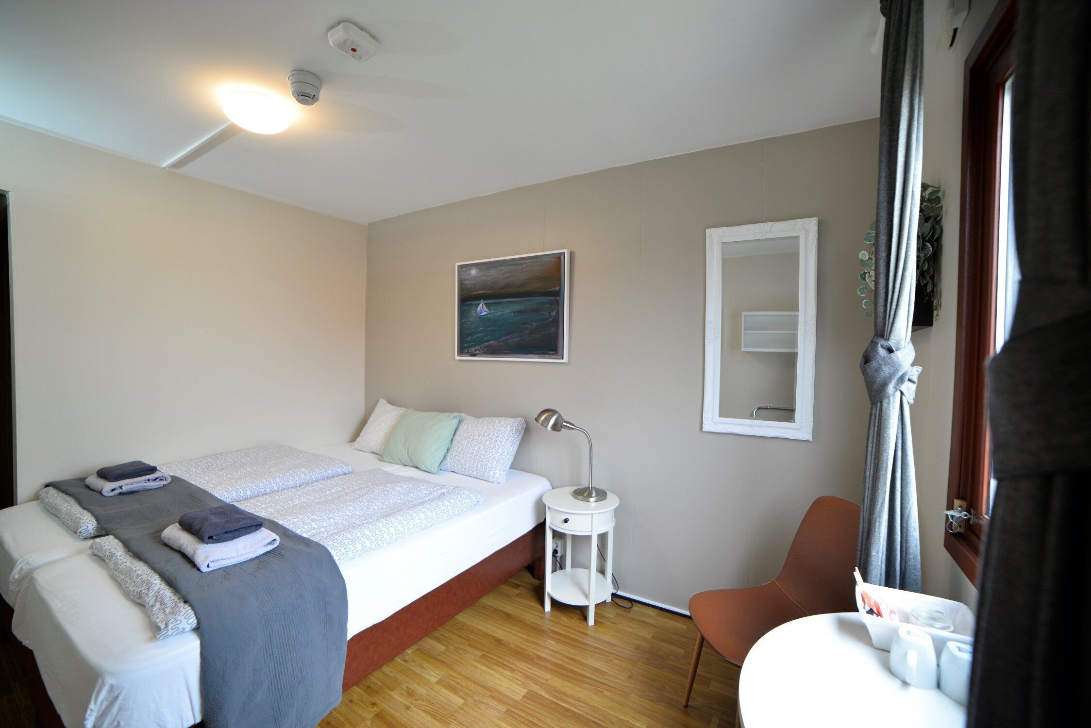 Quarto de hotel com cama, mesa de cabeceira, cadeira e um quadro na parede.