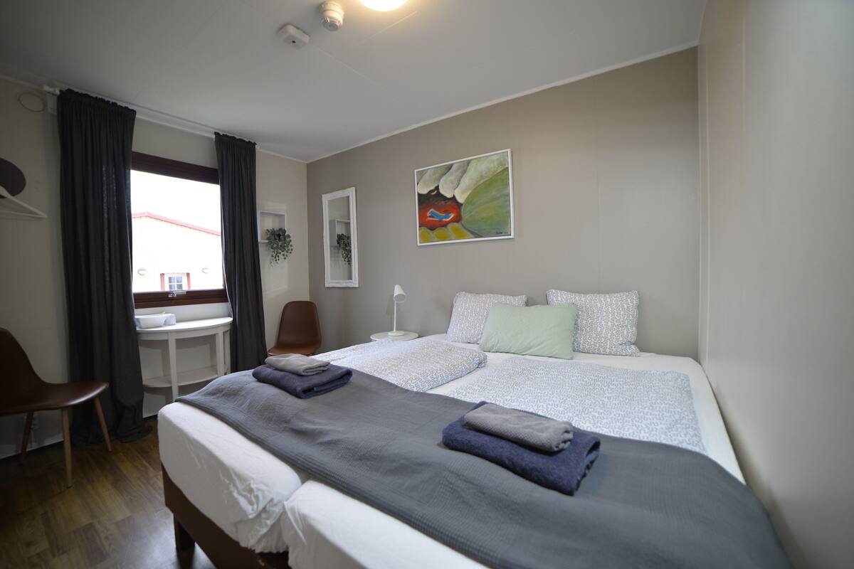 Quarto de hotel com uma cama, uma escrivaninha e uma cadeira.