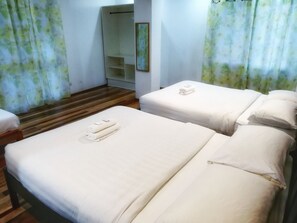 Quarto de hotel com duas camas, piso de madeira e cortinas florais.
