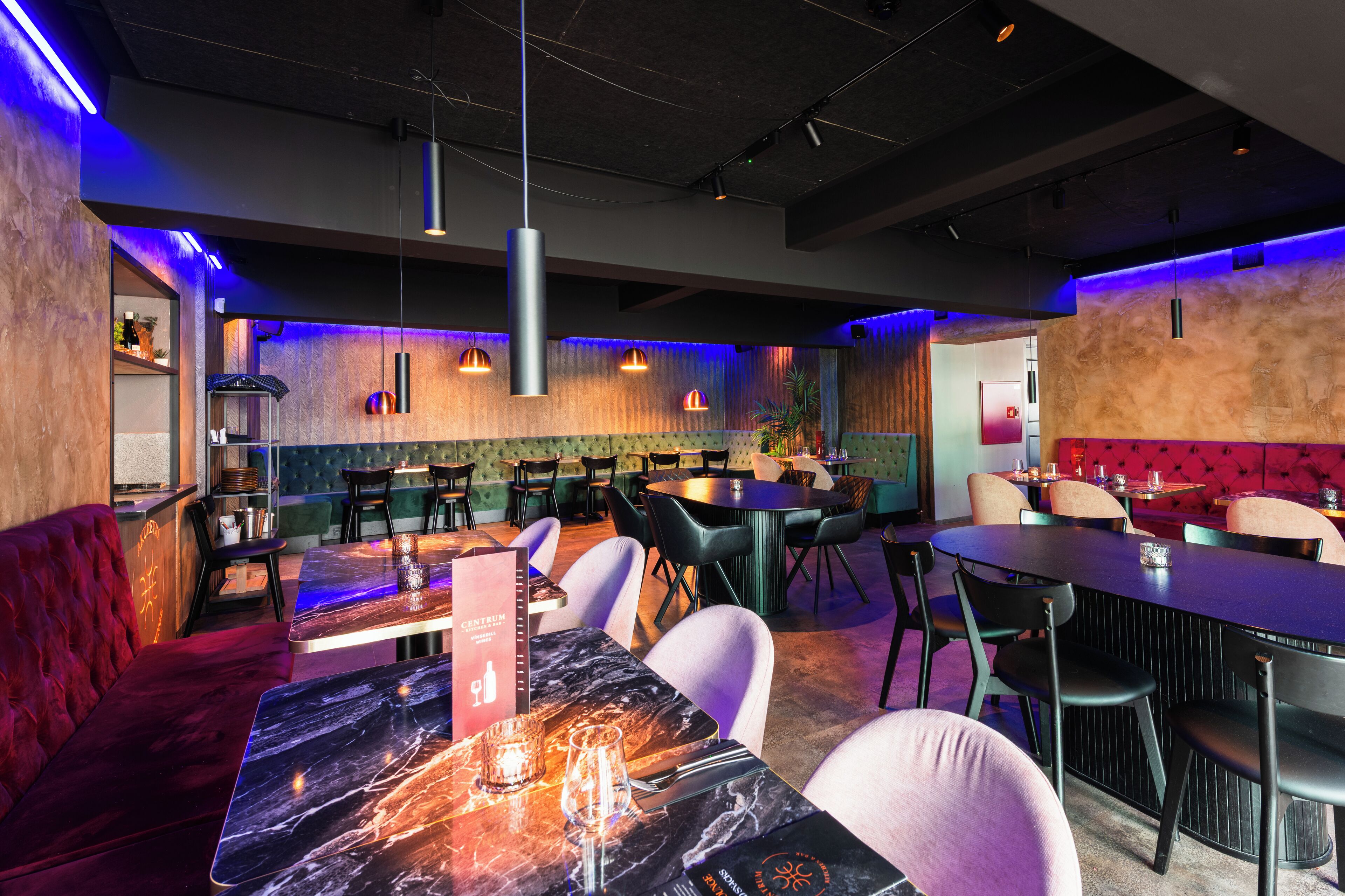 Um restaurante moderno com mesas de bancada de mármore, assentos acolchoados e iluminação ambiente.