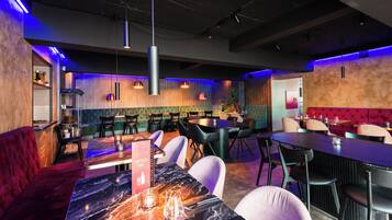 Um restaurante moderno com mesas de bancada de mármore, assentos acolchoados e iluminação ambiente.