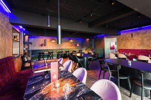 Um restaurante moderno com mesas de bancada de mármore, assentos acolchoados e iluminação ambiente.