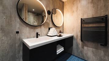 Um banheiro moderno com uma pia branca, dois espelhos redondos, um porta-toalhas preto e um chão em azulejos azuis.