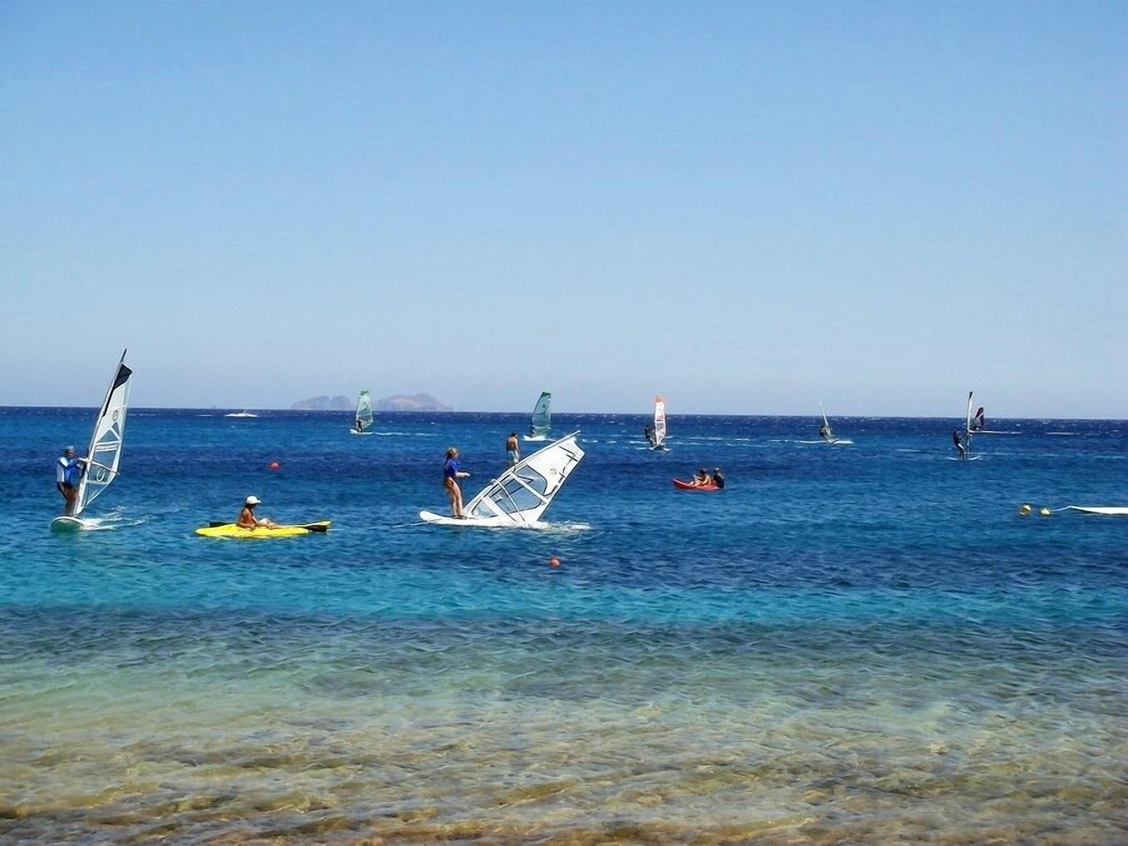 Mar azul e límpido com várias atividades de windsurf.