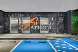 Um elevador moderno com uma grande logo laranja e o texto 'Fiesta Americana' na parede.