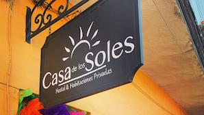 Placa de 'Casa de los Soles Hostel' com decoração florida colorida.