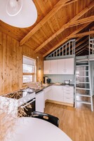 Interior em madeira com cozinha, incluindo fogão, pia e armários.