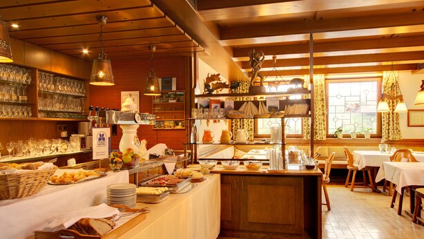 Uma área de buffet com diversos alimentos, um espaço para café e uma área de estar com mesas e cadeiras.