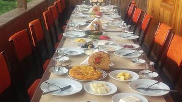 Uma longa mesa de jantar posta para uma refeição, com diversos pratos e utensílios.