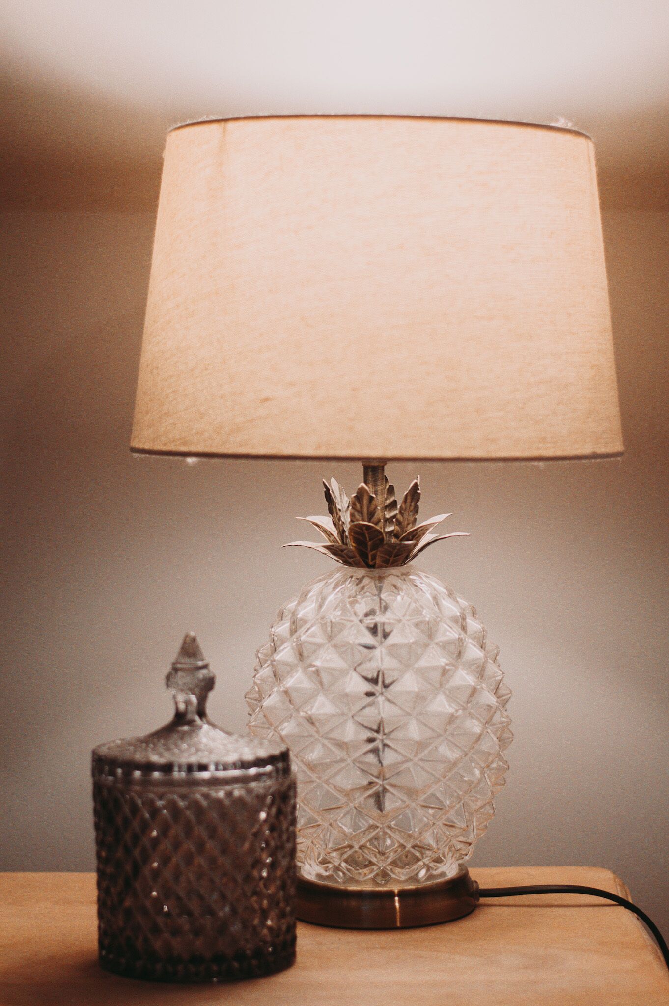 Uma luminária com base texturizada e cúpula decorativa, sobre uma superfície de madeira.