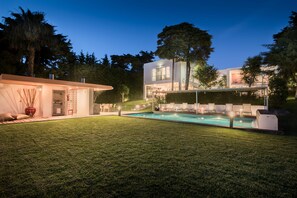 Uma casa moderna com piscina, varanda coberta e gramado bem cuidado.