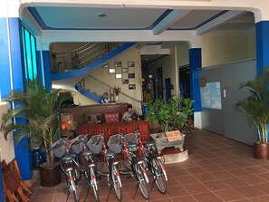 Uma área de recepção com escadas, balcão de atendimento e várias bicicletas estacionadas.