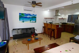 Sala de estar com sofá, mesa de centro e um quadro de uma praia.