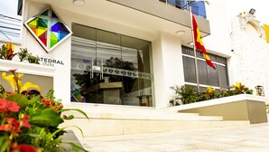 Entrada de hotel com fachada de vidro, uma bandeira e uma placa com a inscrição "HOTEL FEDERAL INN".