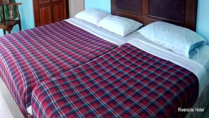 Quarto com cabeceira de madeira, colcha xadrez e almofadas brancas.