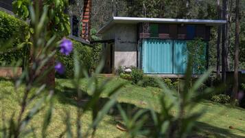 Uma casa moderna com fachada de vidro, rodeada por vegetação exuberante e um gramado bem cuidado.