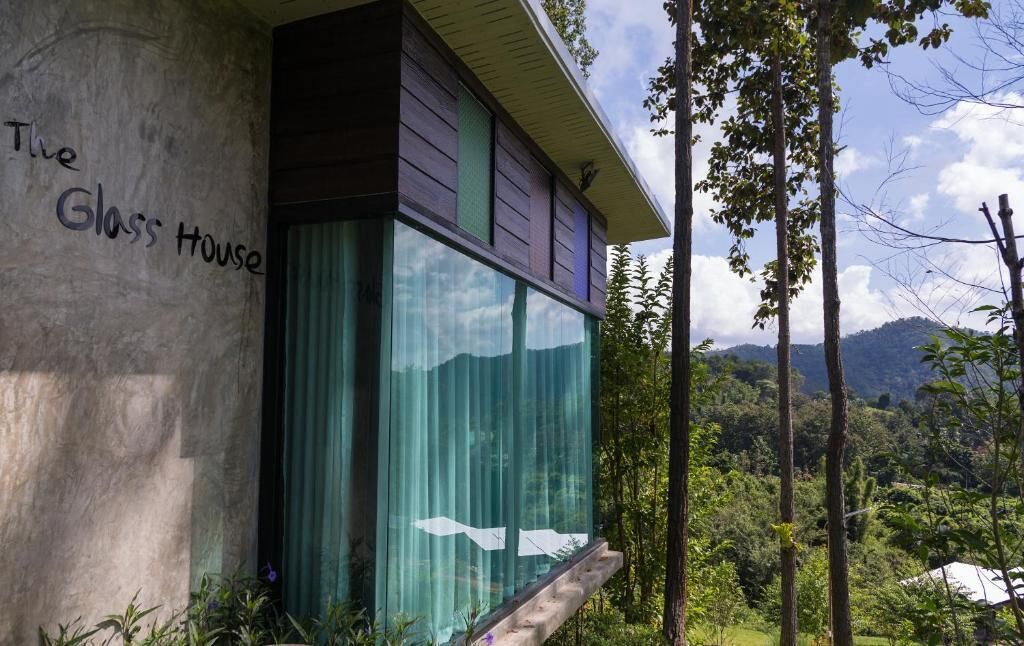 Um edifício com fachada de vidro e uma placa com a inscrição 'The Glass House'.