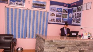 Uma mesa de recepção com bancada de pedra, uma cadeira de couro preto e uma cortina listrada em azul.
