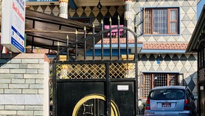 Um edifício de vários andares com um portão de entrada imponente, varandas e a placa de um albergue turístico.