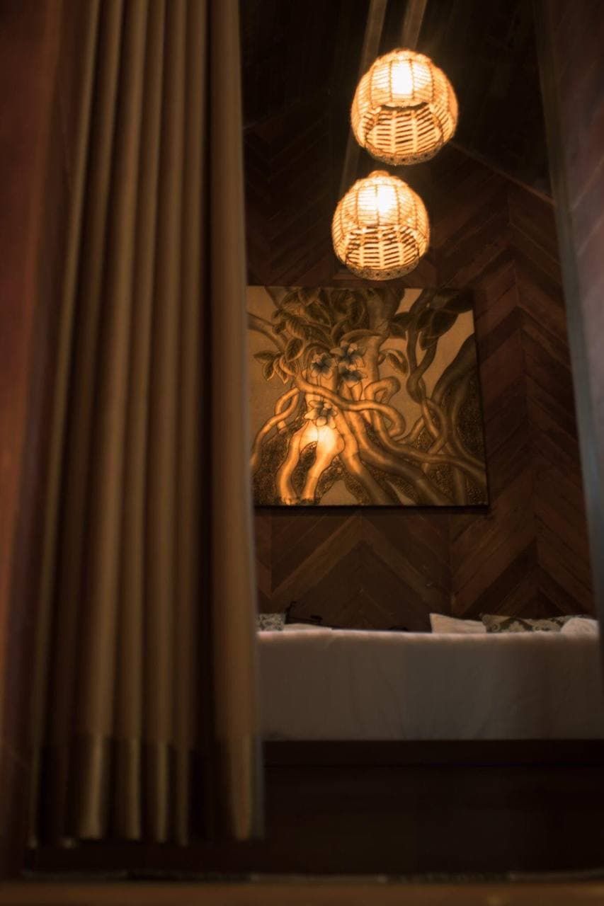 Quarto com cama, um quadro na parede e duas luminárias de vime penduradas.