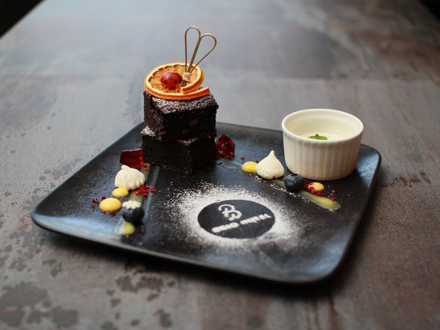 Um prato de sobremesa com bolo de chocolate, uma pequena tigela e diversos enfeites.