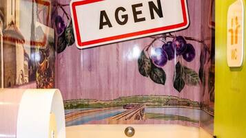 Um banheiro com vaso sanitário, secador de mãos e uma placa na parede com a inscrição 'AGEN'.