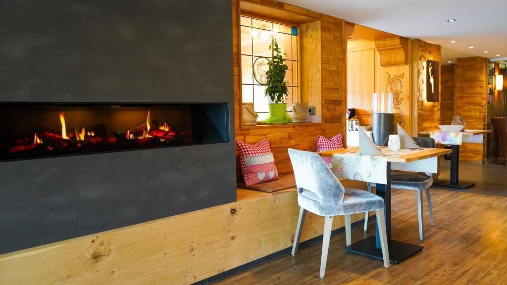 Um interior moderno com lareira, detalhes em madeira e uma área de refeições com cadeiras e mesa.