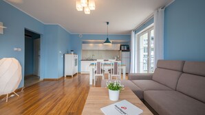 Um apartamento moderno com área de jantar, cozinha e sala de estar com sofá e mesa de centro.