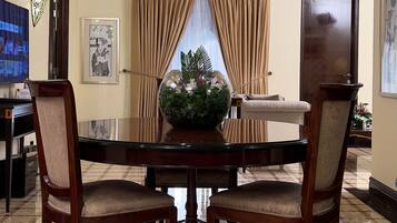 Uma sala de jantar com uma mesa redonda, quatro cadeiras, um ventilador de teto e uma taça decorativa sobre a mesa.