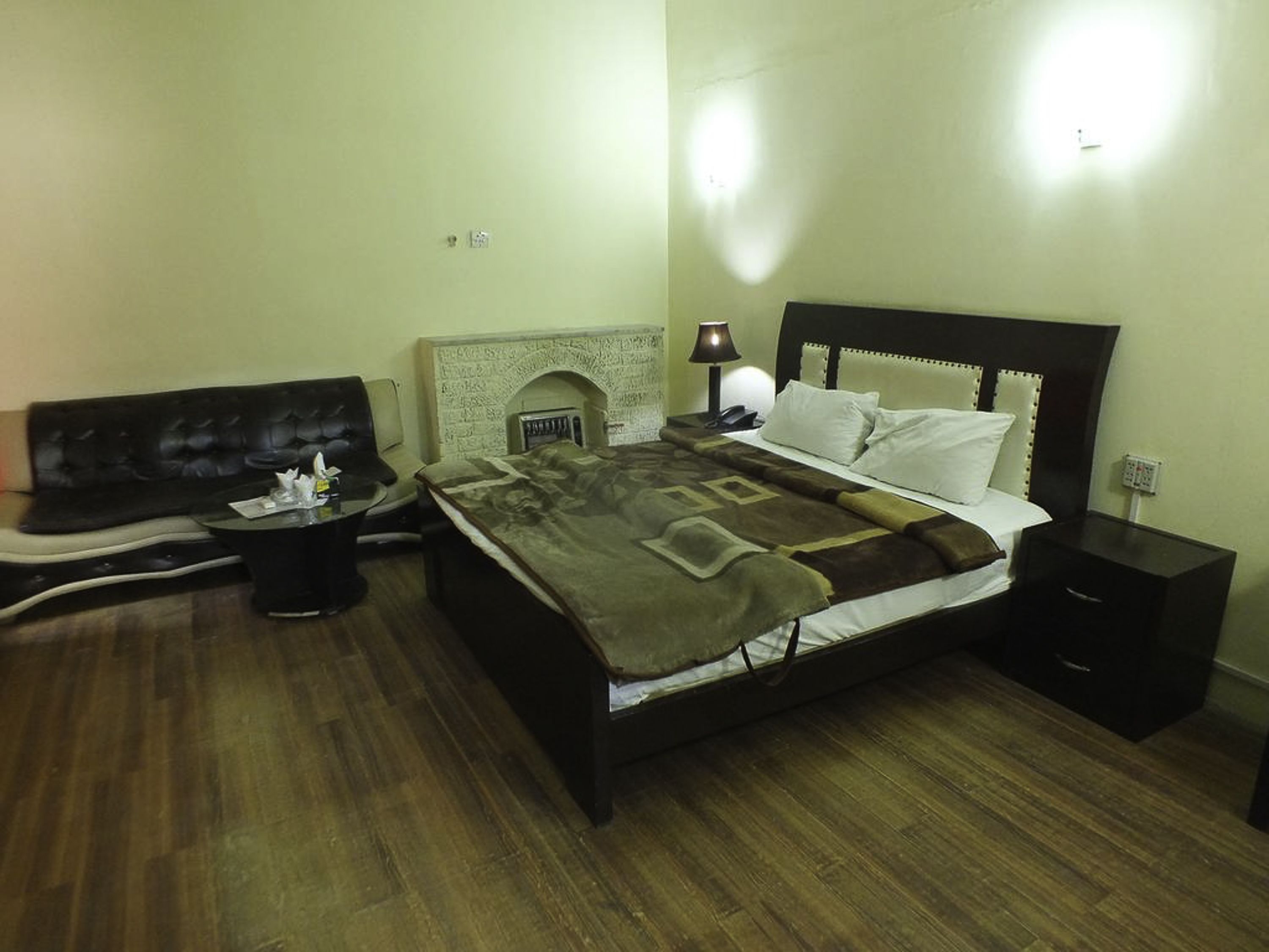 Quarto com cama, mesas de cabeceira, luminária e lareira.