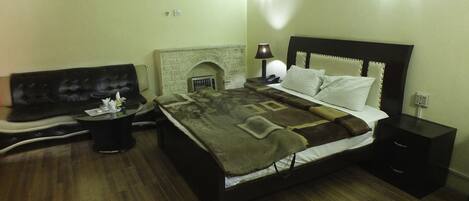 Quarto com cama, mesas de cabeceira, luminária e lareira.