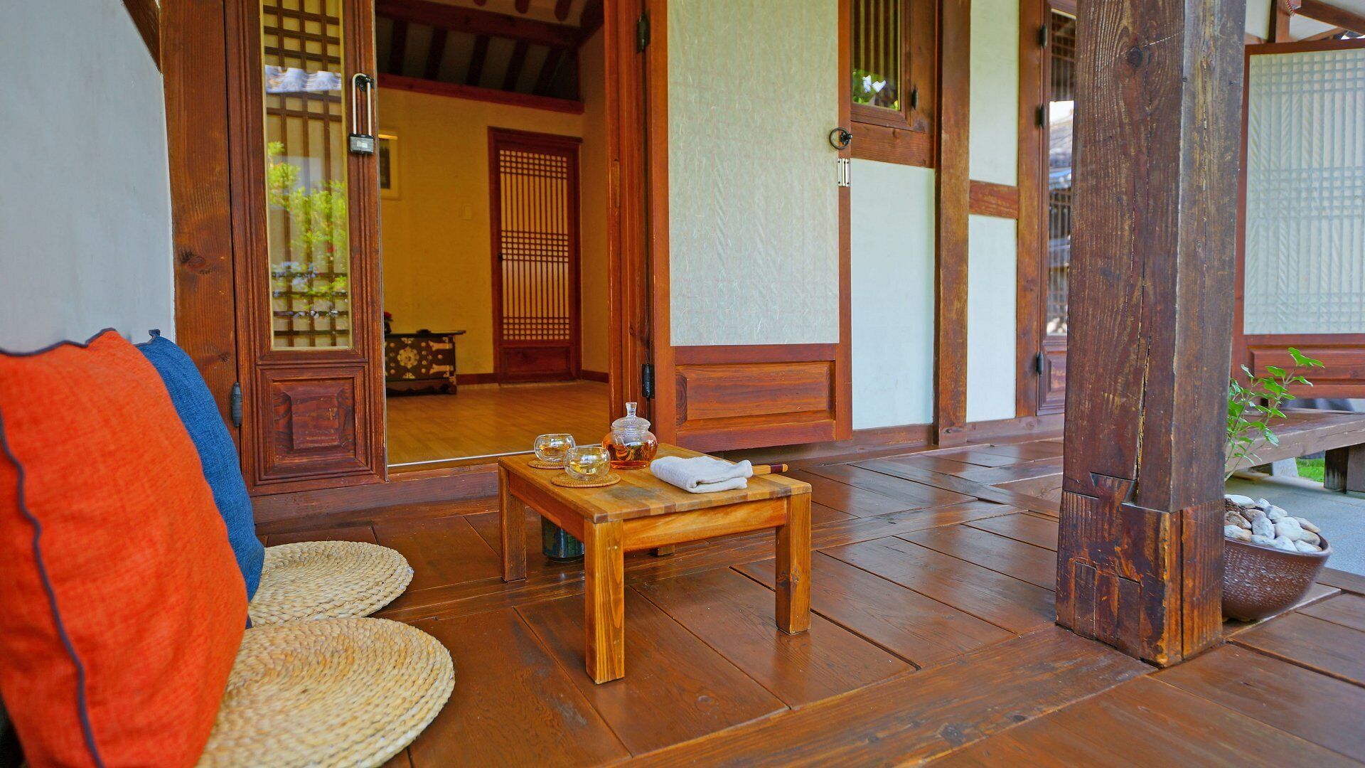 Um quarto em estilo japonês tradicional, com tatames, uma mesa de madeira baixa com jogo de chá e uma porta deslizante que dá para outro cômodo.