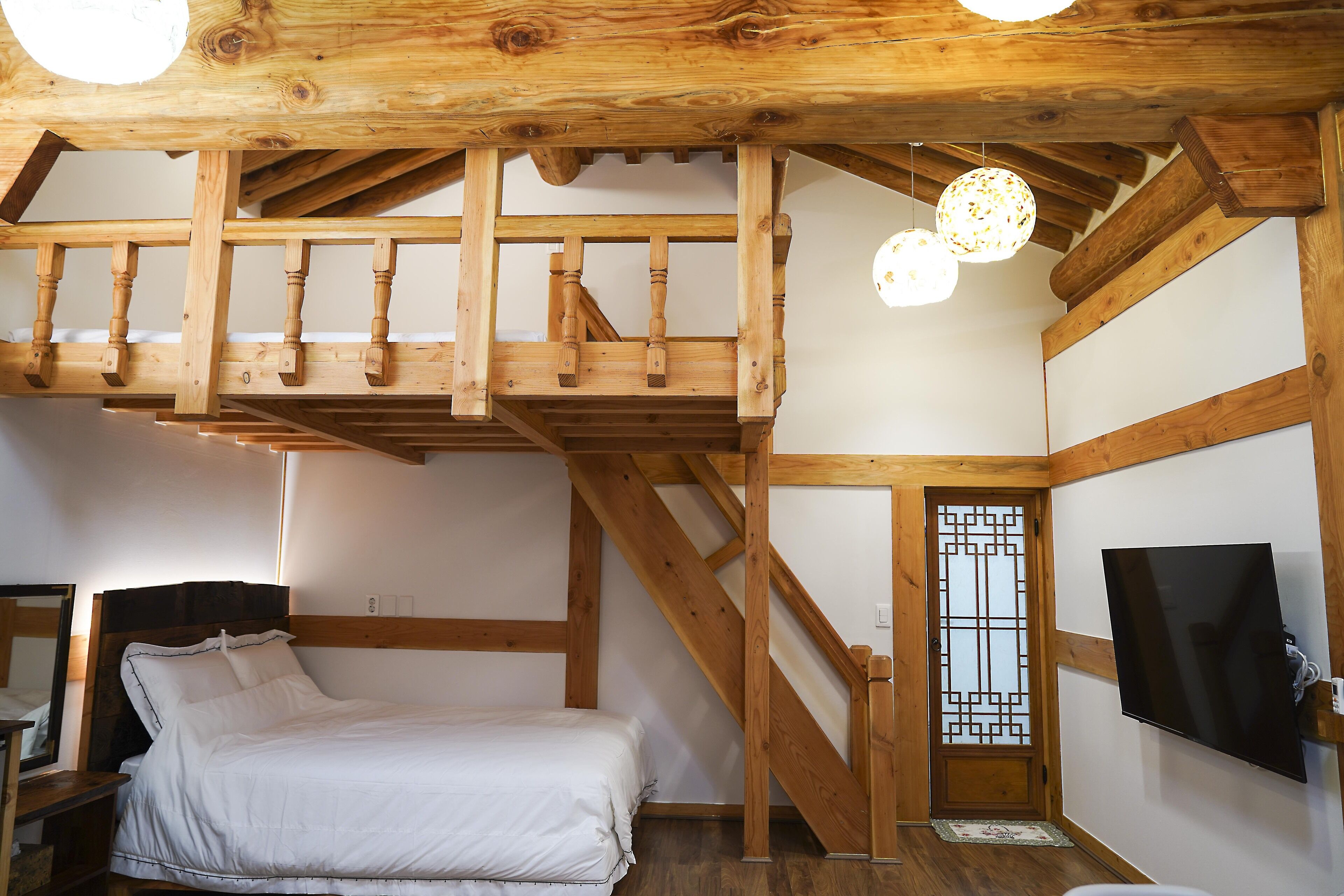 Quarto de madeira com uma cama, uma TV e uma escada.