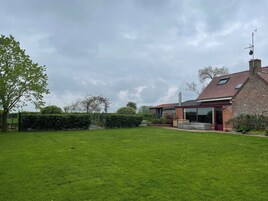 Uma casa com fachada de tijolos, uma grande porta de vidro e um gramado bem cuidado.