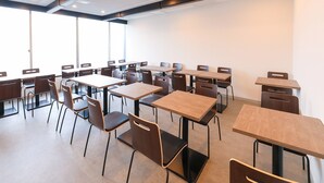 Uma sala de aula moderna com fileiras de mesas e cadeiras, janelas amplas e teto com iluminação embutida.