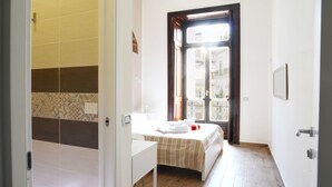 Quarto de hotel com cama, mesa de cabeceira, banheiro com vaso sanitário e pia, e varanda com vista.