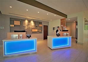 Uma área de recepção de hotel com dois balcões, design de interiores moderno e um recepcionista.