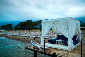 Uma cabana à beira-mar com toldo, cadeiras de lounge e uma pequena mesa.