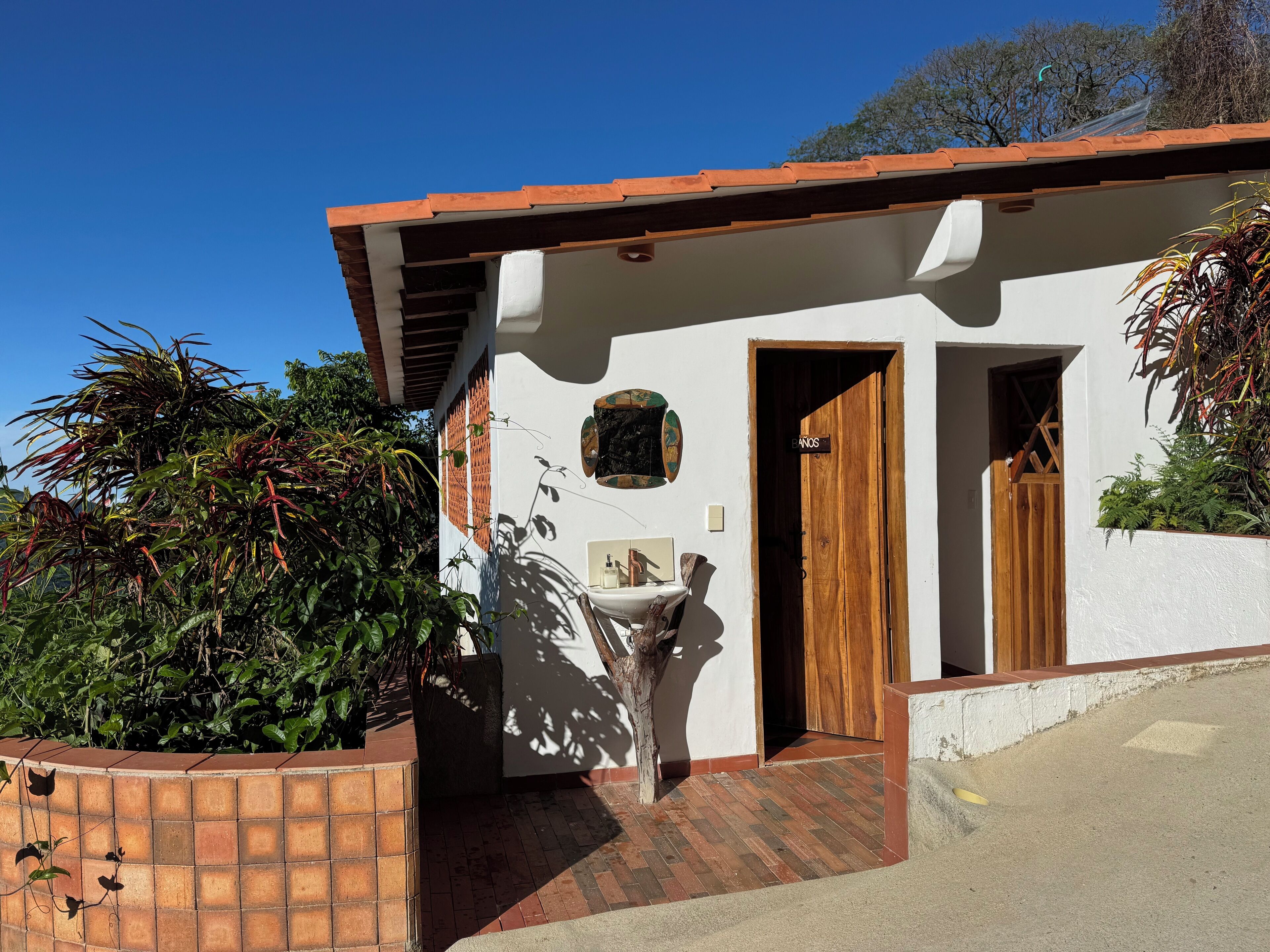 Uma casa com entrada em azulejos, porta de madeira e piazinha externa.