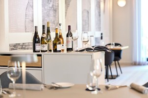 Uma área de refeições com uma seleção de vinhos em um balcão, uma mesa com talheres e um design de interiores moderno.