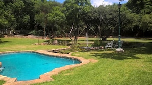Quintal com piscina, pequena área de jardim e um poste de luz.