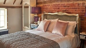 Quarto com cama, lustre e parede de tijolos com afresco.