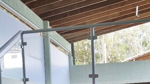 Uma área de pátio coberta com uma mesa e cadeiras de madeira, cercada por plantas em vasos.