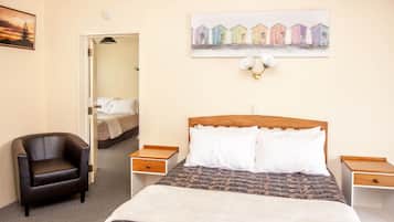 Quarto de hotel com cama, cadeira, mesa de cabeceira e luminária na parede.