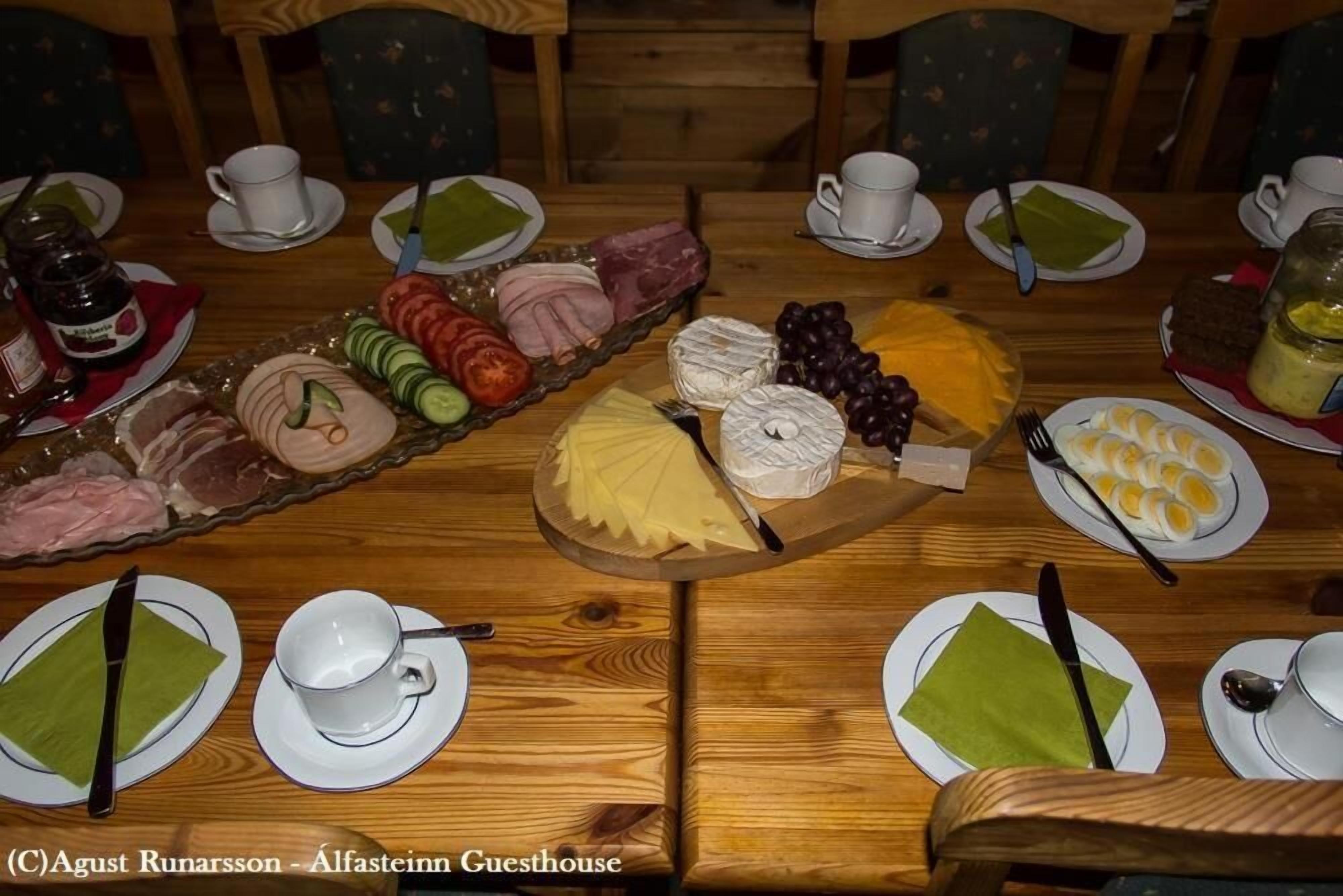 Mesa de café da manhã com diversas opções de alimentos, incluindo carnes, queijos e frutas.