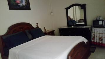 Quarto com cama de madeira, penteadeira, espelho e televisão.