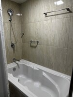 Casa de banho moderna com banheira, chuveiro e porta-toalhas.