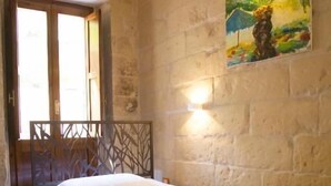 Quarto com cama, janela e um quadro na parede.