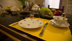 Uma mesa de jantar com um prato, faca e bule sobre um jogo americano amarelo.